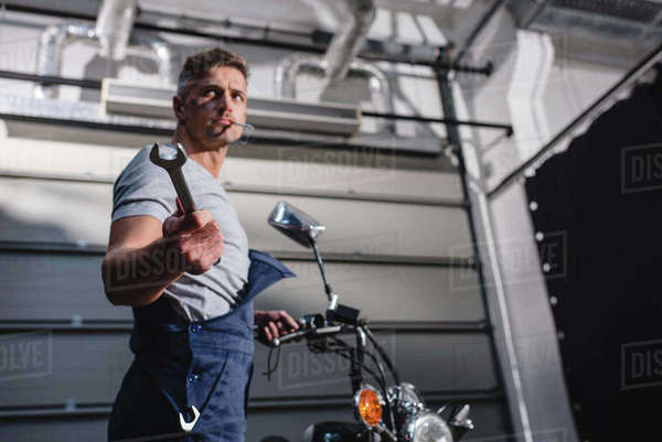 Mechanic smoking cigarette and holding wrench - Royalty-free Stock ...