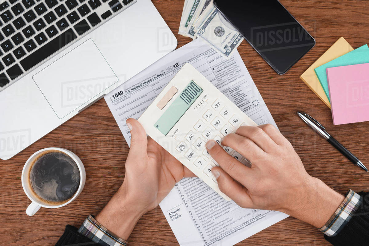 Cropped view of man using calculator with tax form and laptop on ...