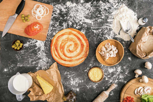 Top view of uncooked pizza and ingredients on grey background with ...