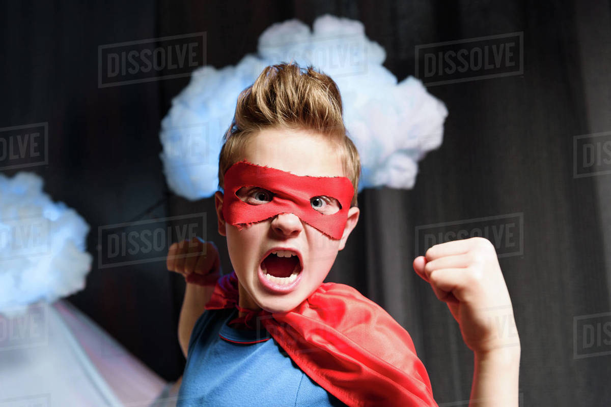 Boy in red superhero costume with fighting gesture screaming and ...