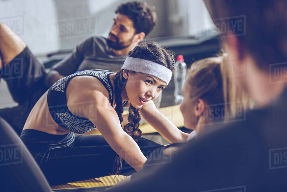 Sporty young people lying on yoga mats and exercising at the gym ...