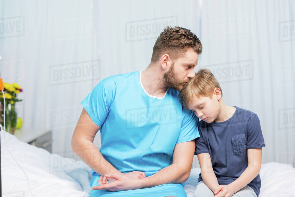 Sick father and upset son sitting together on hospital bed, dad and son ...