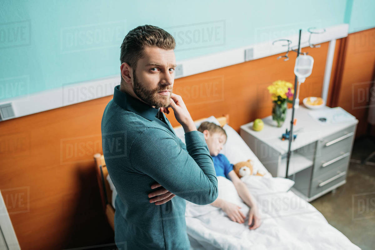 High angle view of dad standing near sick son in hospital bed - Royalty ...