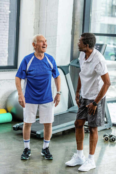 Cheerful multiethnic sportsmen talking to each other at gym - Royalty ...