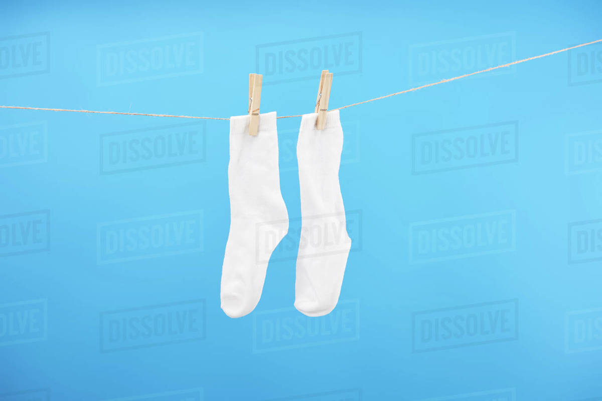 Clean white socks hanging on clothesline isolated on blue background ...