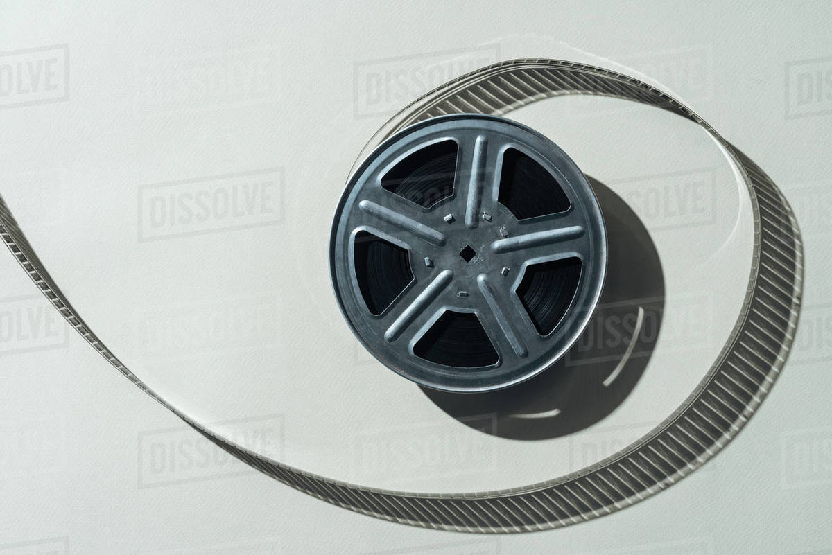 Top view of film reel with twisted cinema tape on grey background ...
