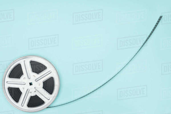 Movie reel with cinema tape isolated on blue - Stock Photo - Dissolve