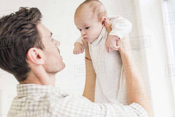 Side view of young father and little baby at home - Stock Photo - Dissolve