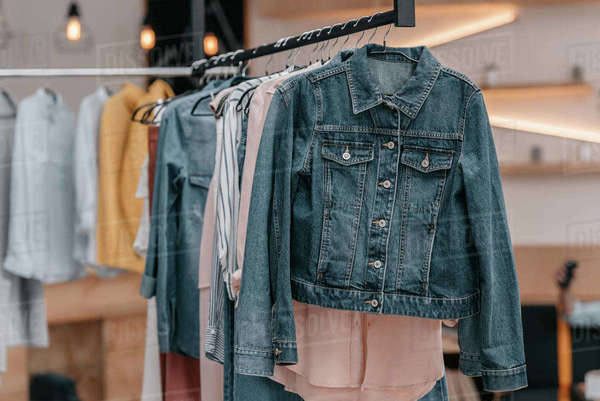 Close-up view of various stylish clothes hanging on hangers in boutique ...