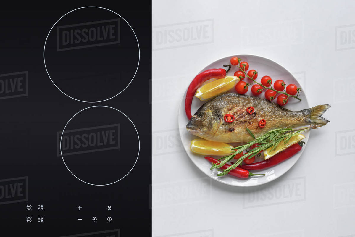 Top view of gourmet fried fish with lemon, chili peppers, rosemary and ...