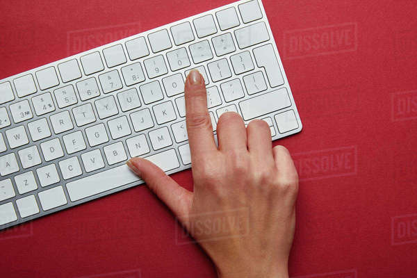 Top view of woman pushing button on white computer keyboard on red ...