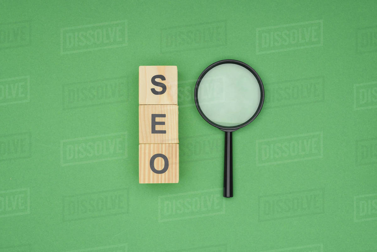 Top view of wooden blocks with letters and magnifier on green ...