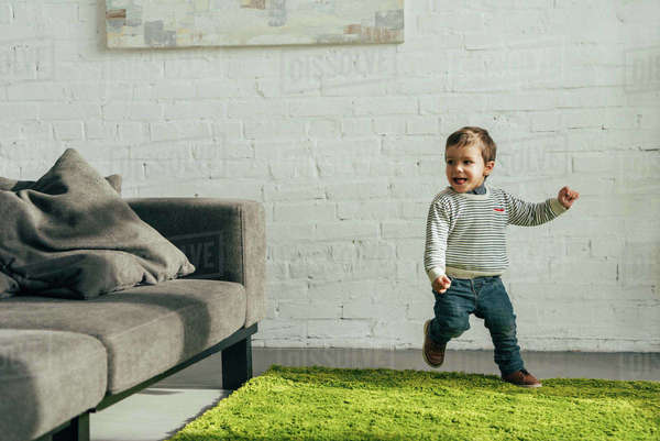 Happy little boy running in living room at home - Stock Photo - Dissolve