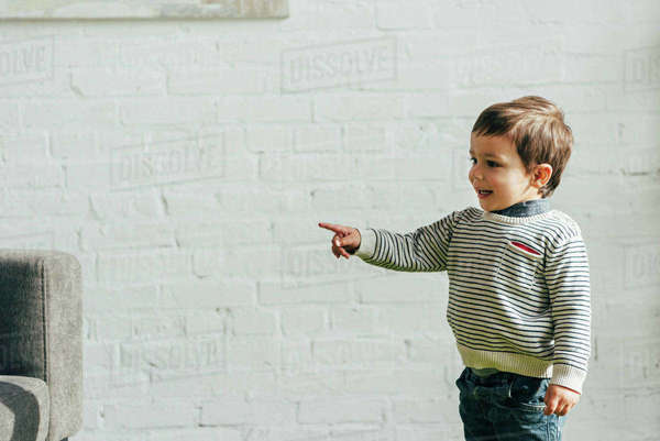 Smiling little child pointing by finger in living room at home - Stock ...