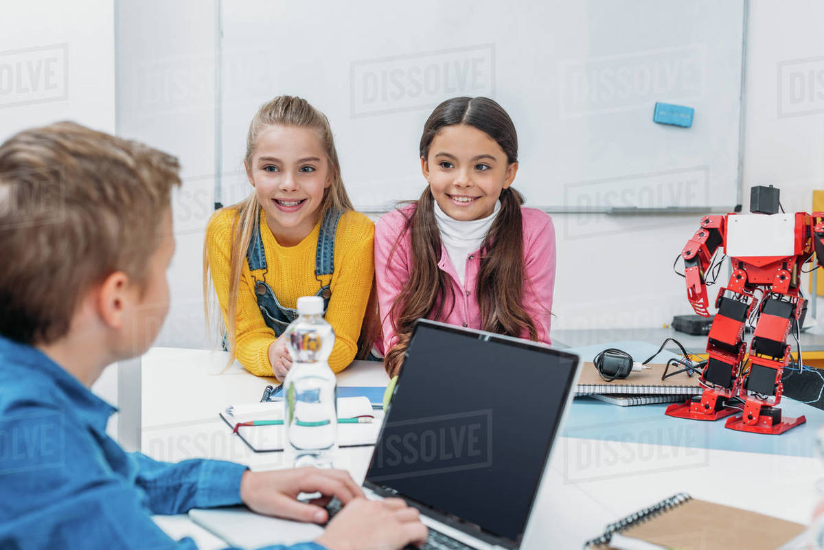 Schoolchildren programming robot together and using laptop during stem ...