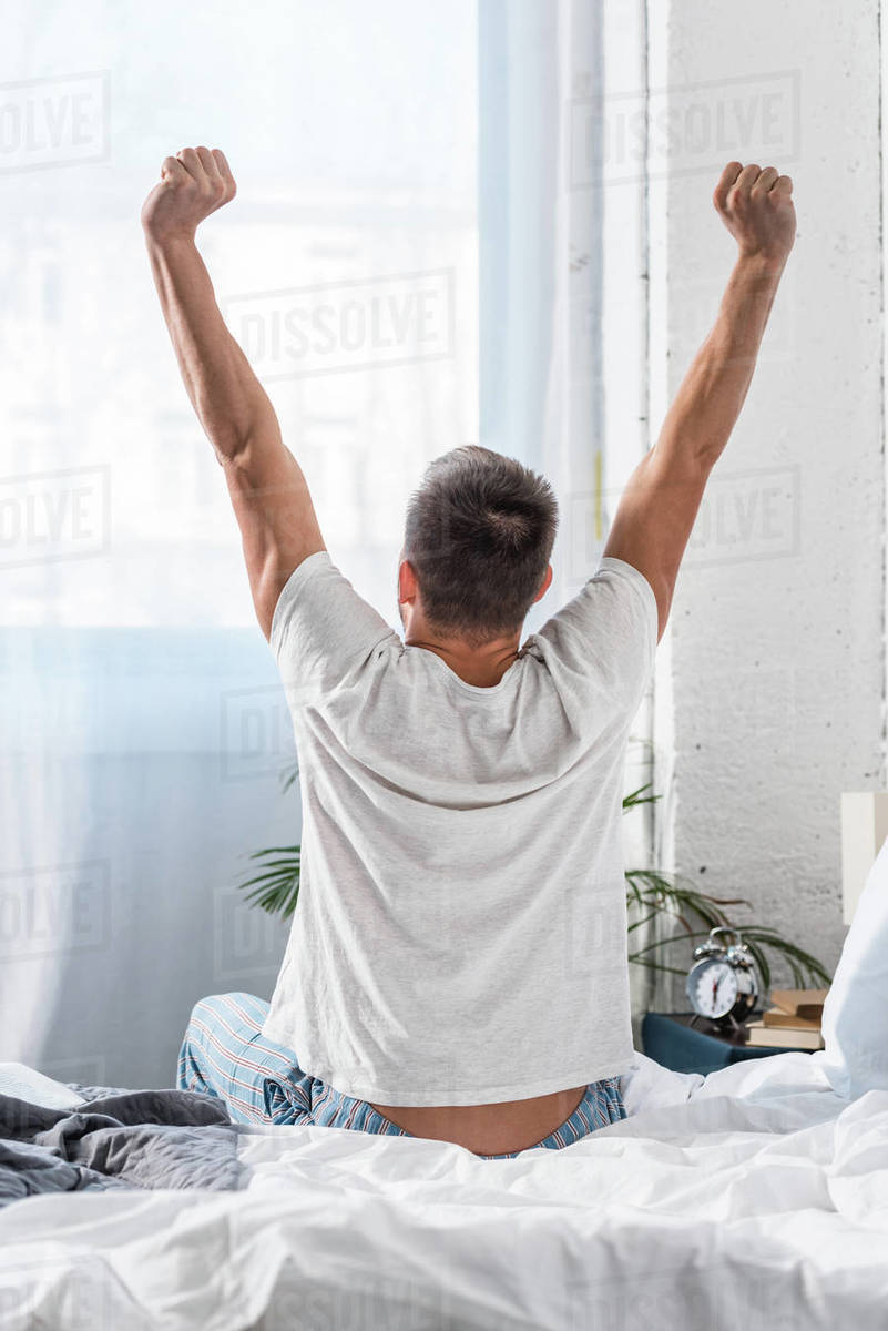 Back view of man stretching in morning in bedroom - Royalty-free Stock ...