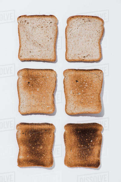 Top view of rows of toasts in various roast stages on white surface ...