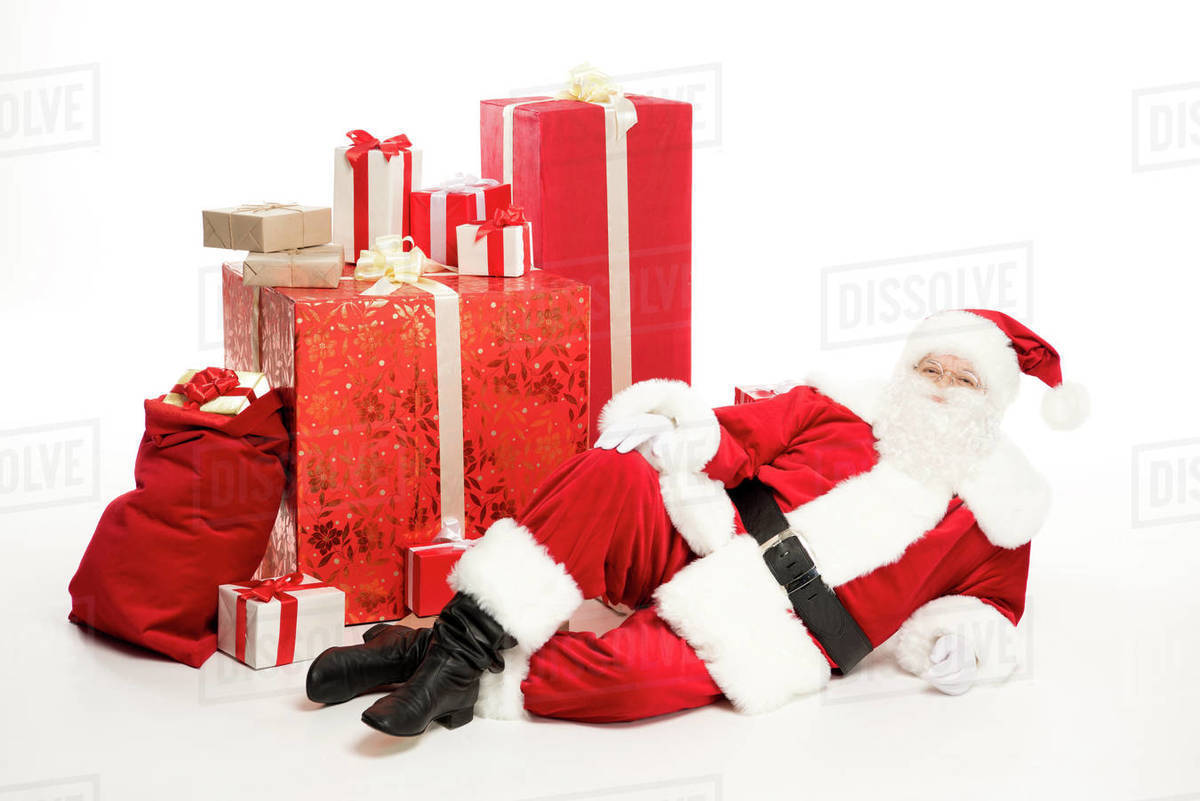Happy Santa Claus lying near a pile of Christmas gifts isolated on ...