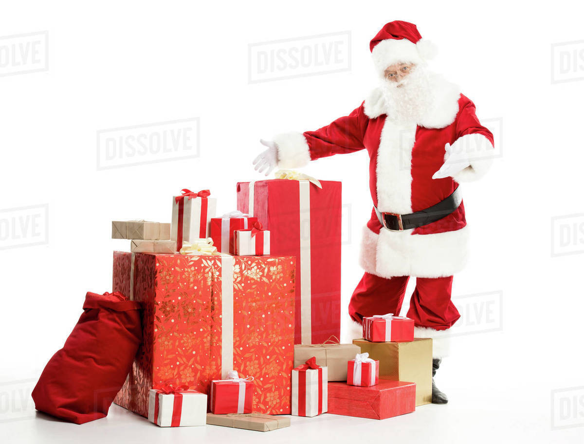 Happy Santa Claus standing with a pile of Christmas gifts isolated on ...