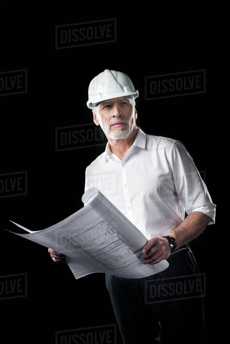 Mature male architect in white hard hat holding blueprints and looking ...