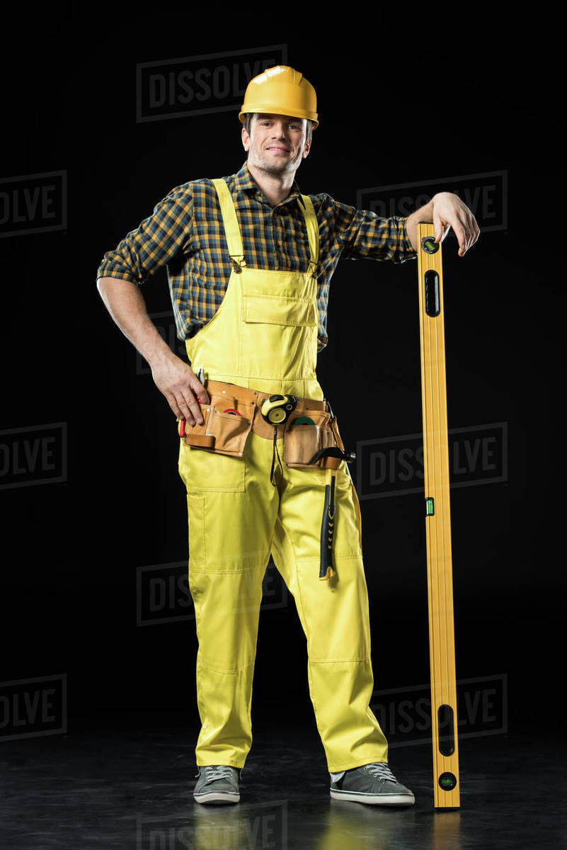 Full length portrait of male construction worker with level tool ...