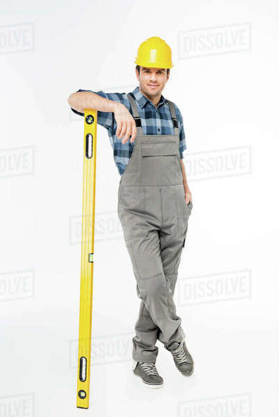 Full length portrait of workman with level tool smiling at camera ...