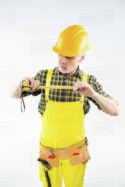 Mature workman in hard hat working with flexible ruler isolated on ...