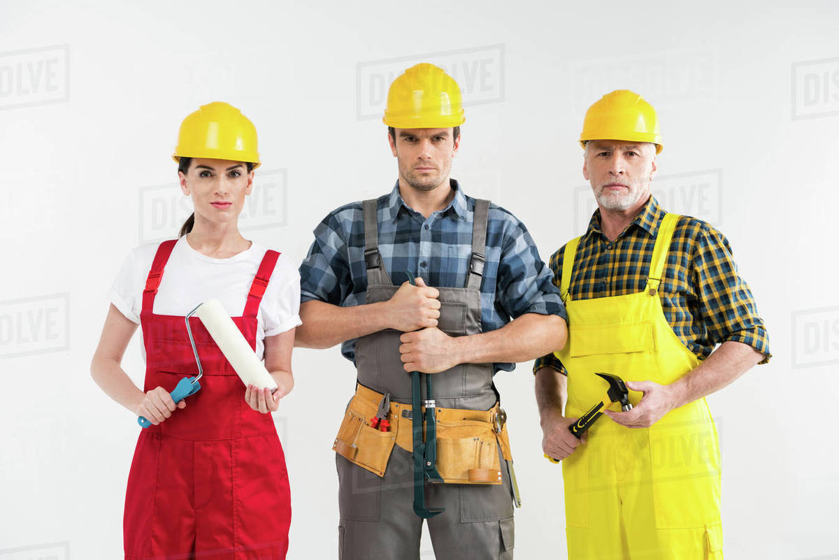 Professional construction workers holding tools and looking at camera ...