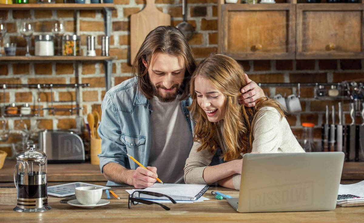 Young happy couple working together with documents and laptop at home ...