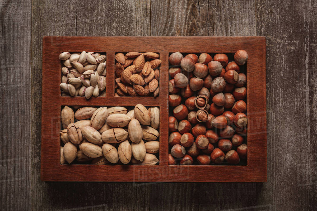 top view of assortment of various nuts in box on wooden background ...
