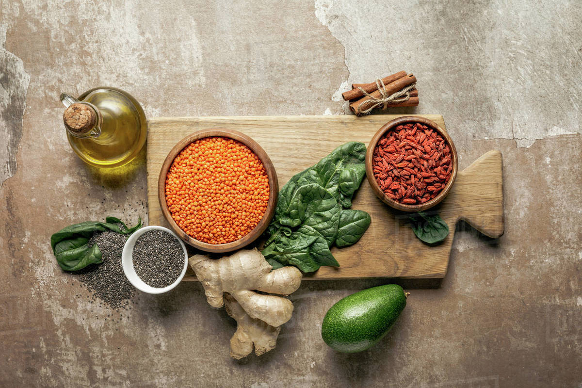 top view of red lentils, ginger, chia seeds and avocado on wooden board ...