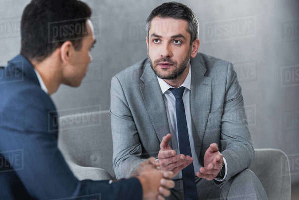 Two serious businessmen in suits sitting and talking together - Royalty ...