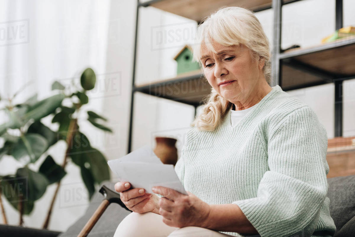 Sad retired woman holding photos in living room - Royalty-free Stock ...