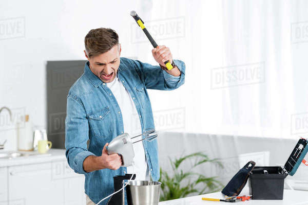Angry adult man screaming and holding mixer and hammer - Stock Photo ...