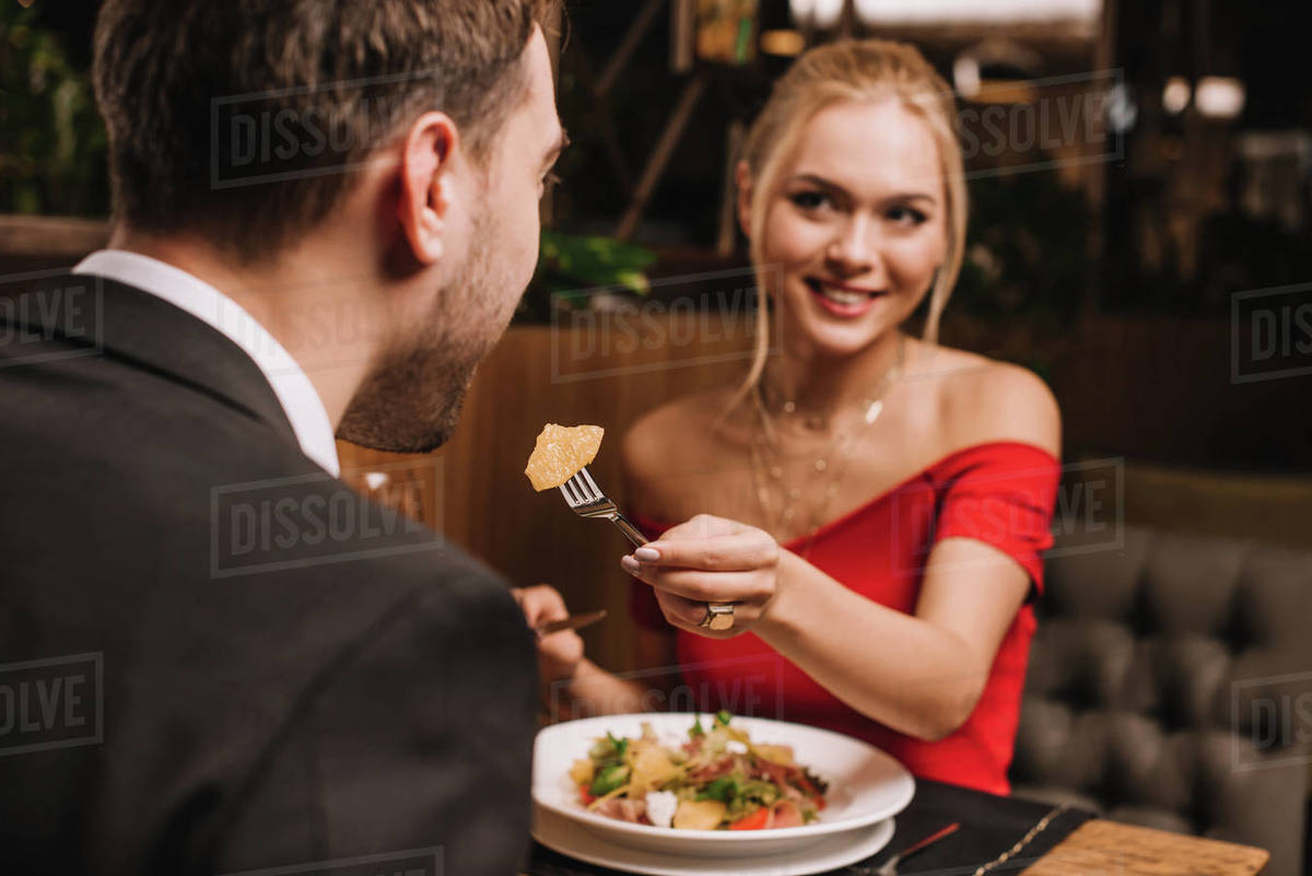 Attractive girlfriend feeding boyfriend in restaurant - Royalty-free ...