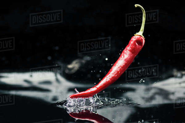 Red chili pepper falling in water isolated on black background - Stock ...