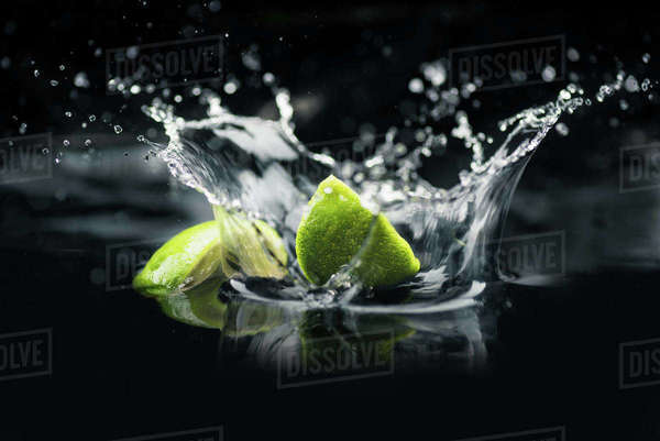 Slices of fresh lime falling in water with splash isolated on black ...