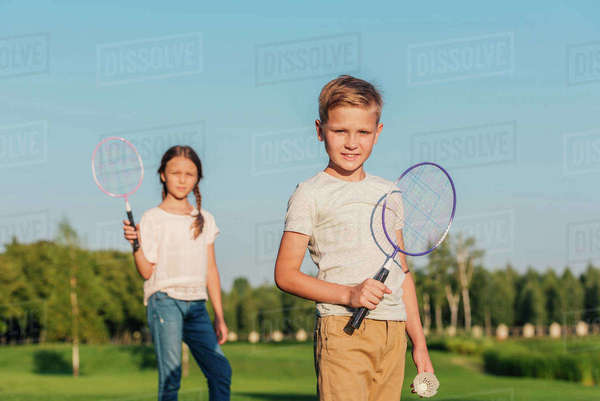 portrait of little boy and girl holding badminton rackets and ...