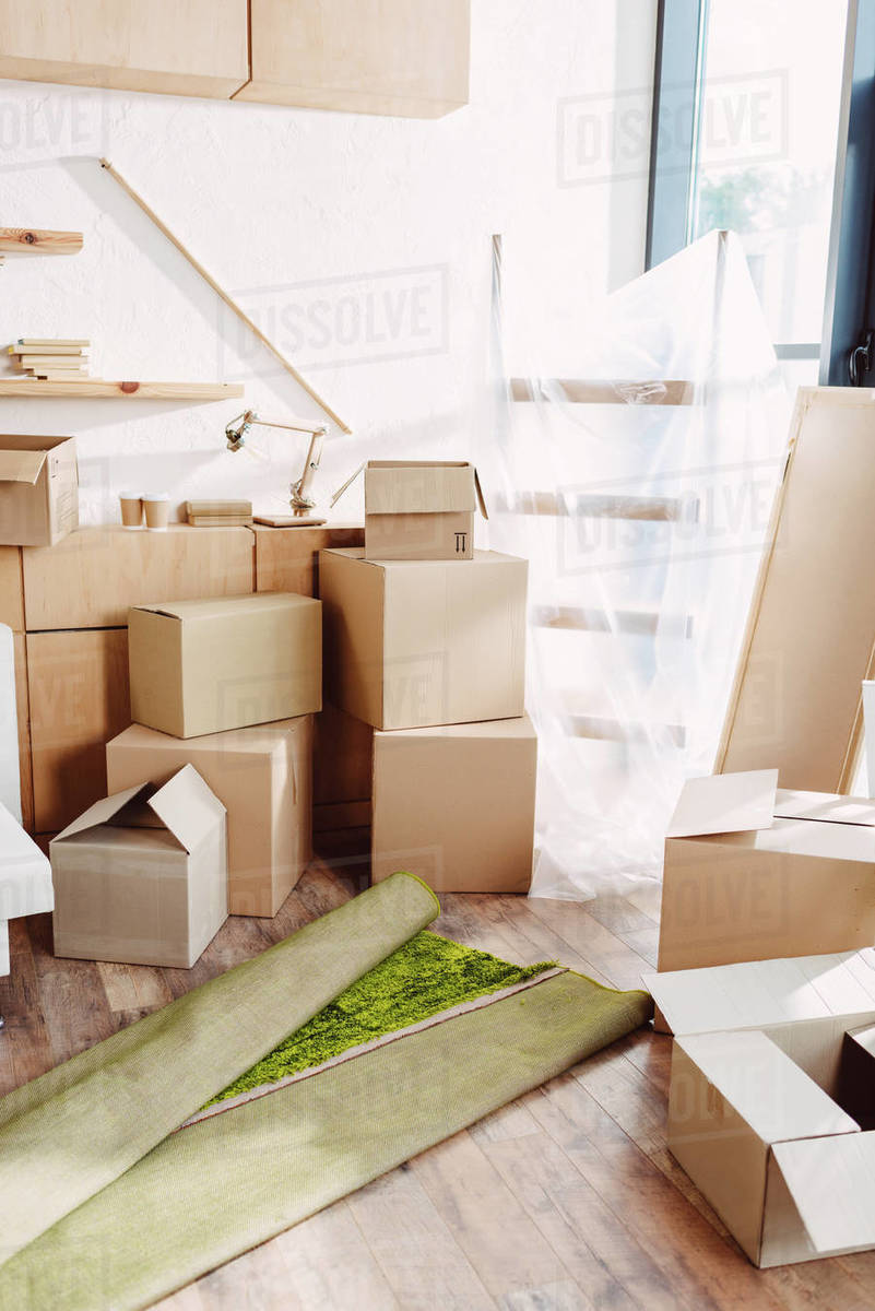 Cardboard boxes and rolled carpet in new house - Stock Photo - Dissolve