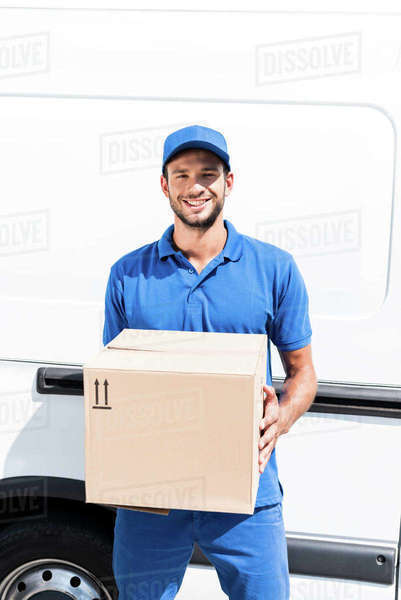 Smiling delivery man with box next to car - Royalty-free Stock Photo ...