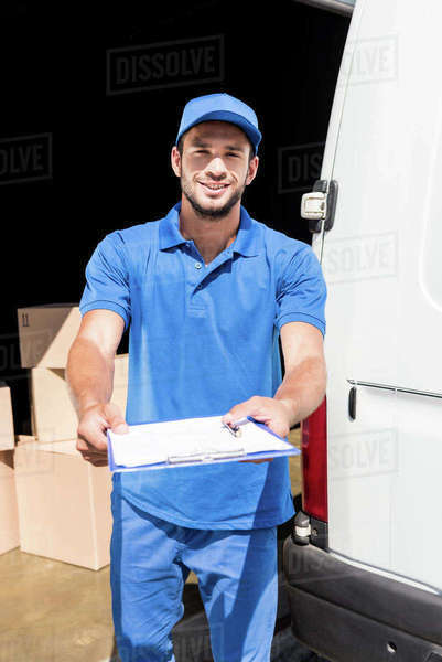 Handsome happy delivery man with clipboard - Royalty-free Stock Photo ...
