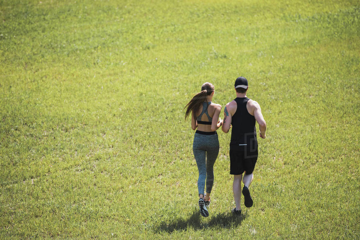Back view of couple in sportswear jogging in park - Royalty-free Stock ...