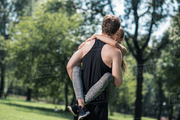 Back view of couple in sportswear hugging each other in park - Royalty ...