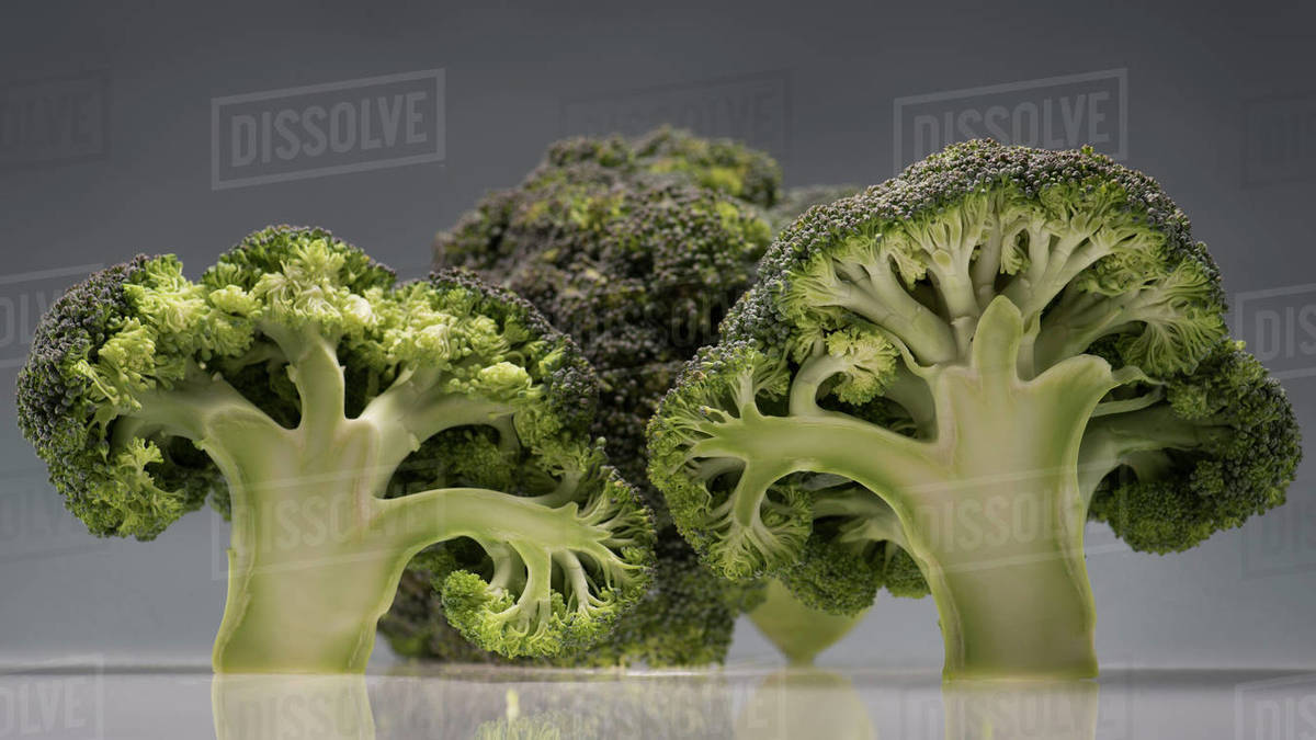 healthy ripe broccoli branches on reflective surface isolated on grey ...