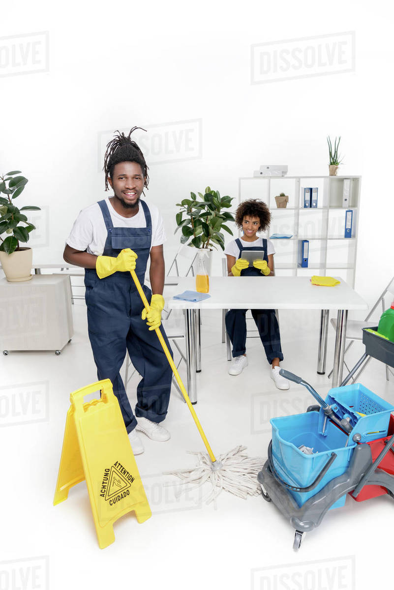 handsome african american cleaner with mop washing floor while female ...