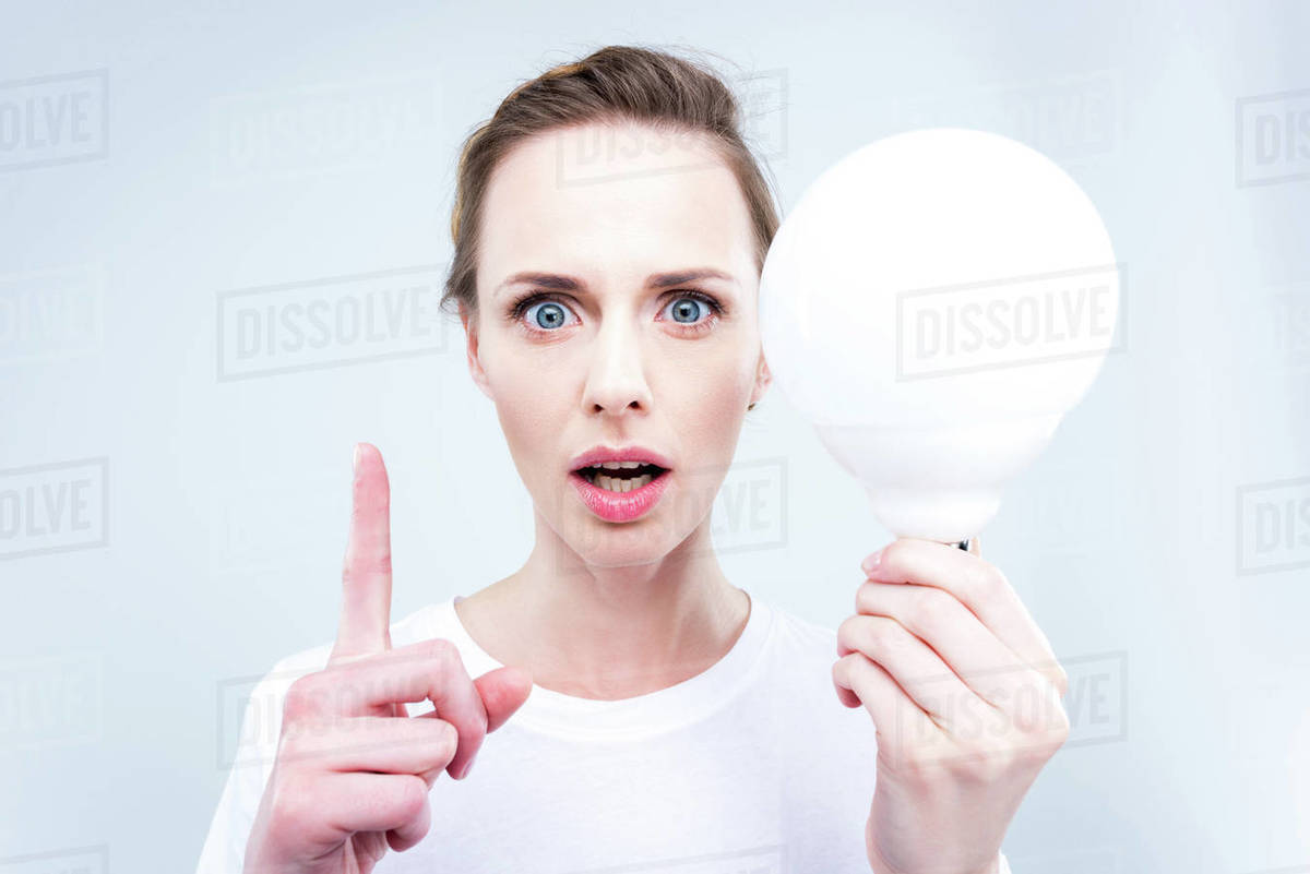 Beautiful woman pointing up and holding light bulb, isolated on white ...