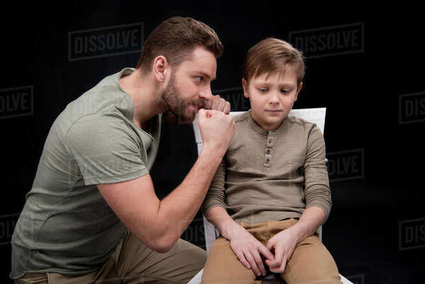 Angry father threatening and gesturing to scared little son sitting on ...