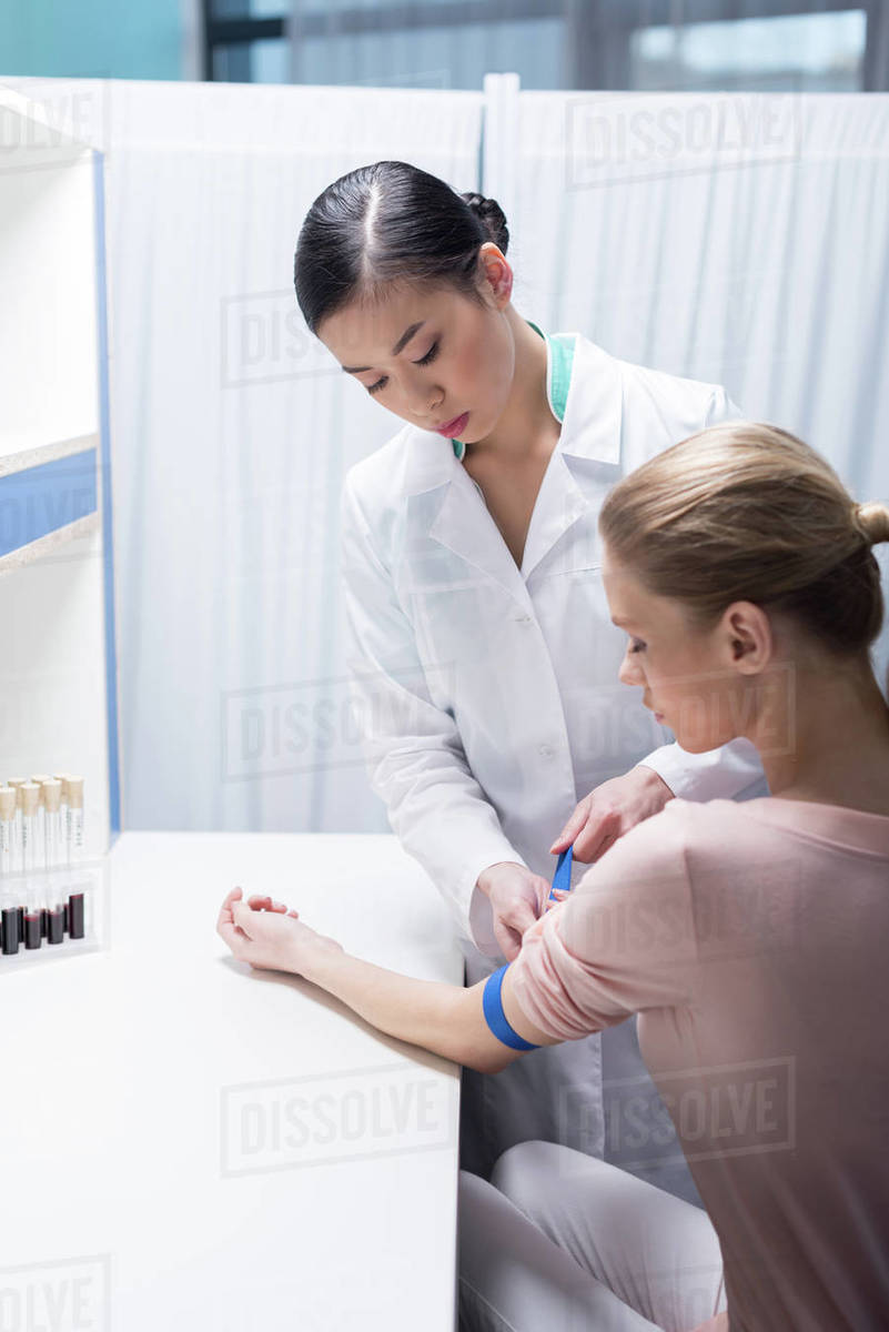 Young doctor preparing patient to do a blood test at laboratory - Stock ...