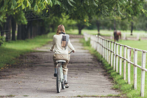 Back view of stylish woman riding bike at countryside - Royalty-free ...