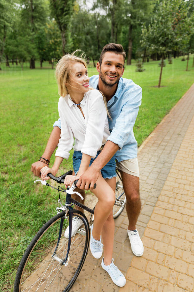 Smiling couple riding bicycle together in park - Royalty-free Stock ...